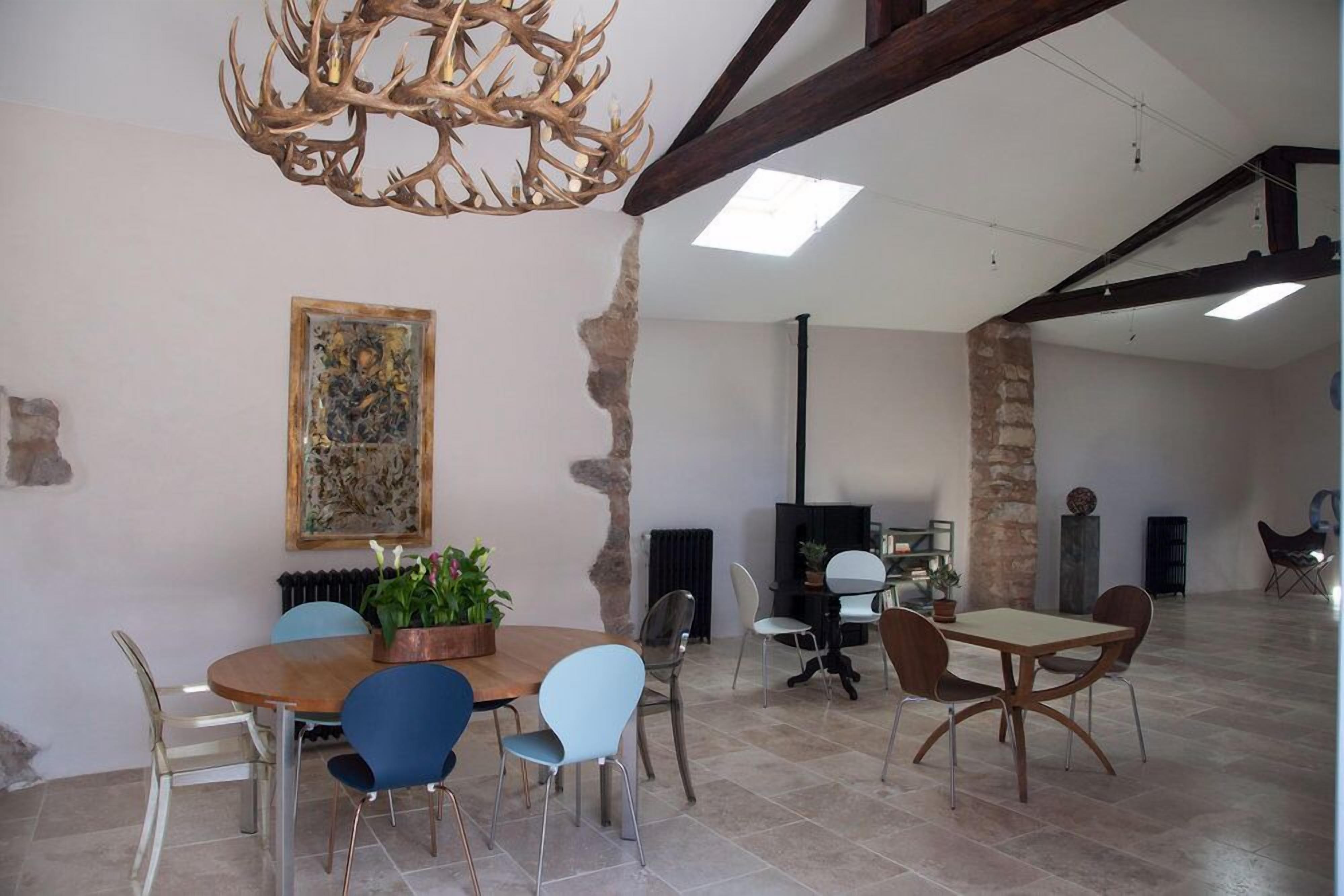 Uma sala de jantar ampla com um lustre rústico, uma pintura grande e uma mistura de móveis modernos e tradicionais.