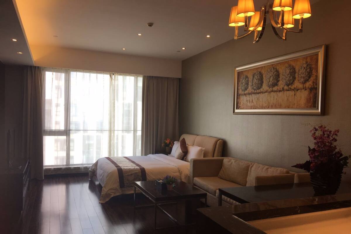 Quarto de hotel com uma cama grande, um sofá, uma mesa de centro e um quadro na parede.