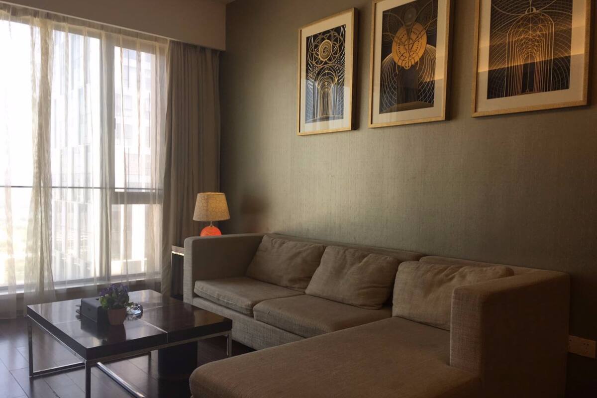 Uma sala de estar moderna com um sofá, uma mesa de centro e uma luminária. Há três obras de arte emolduradas na parede.