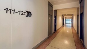 Corredor de hotel com placa indicando os números dos quartos 111 a 120.