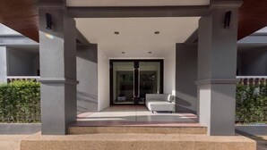 Uma entrada coberta com design moderno, com porta de vidro e um banco branco.