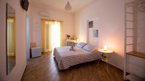Um quarto com cama, mesa de cabeceira, abajur e guarda-roupa.