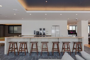 Cozinha moderna com ilha central, banquetas e uma tela grande.