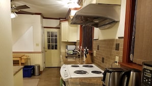 Uma cozinha compacta com fogão, cafeteira e micro-ondas.