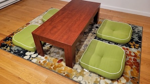 Mesa de madeira com quatro assentos estofados verdes sobre um tapete estampado.