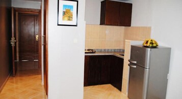 Cozinha com armários de madeira escura, backsplash revestido de azulejos e geladeira de aço inoxidável.