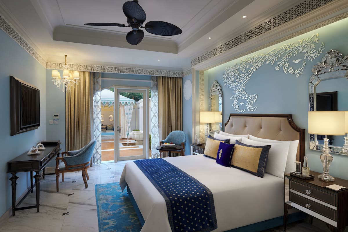 Quarto de hotel espaçoso com uma cama grande, uma escrivaninha e uma cadeira. Há uma varanda com vista para o exterior.