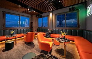 Um lounge moderno com assentos de couro, piso de madeira e grandes janelas com vista para a cidade.