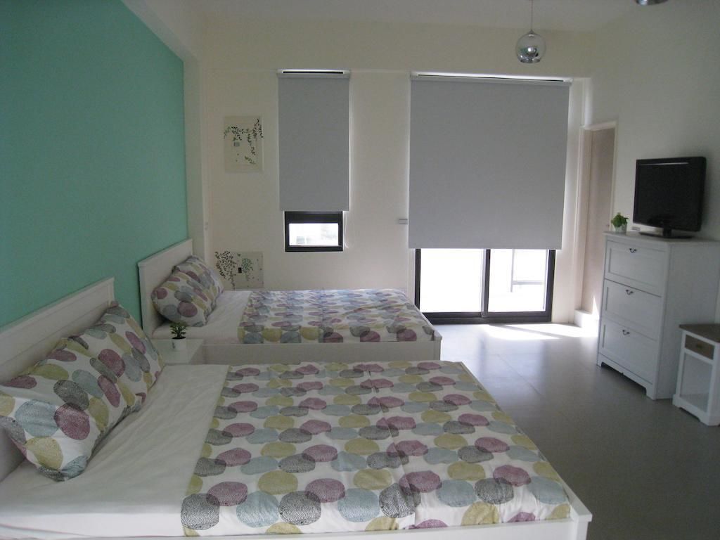 Quarto com duas camas, uma TV e uma cômoda.