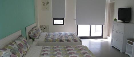 Quarto com duas camas, uma TV e uma cômoda.