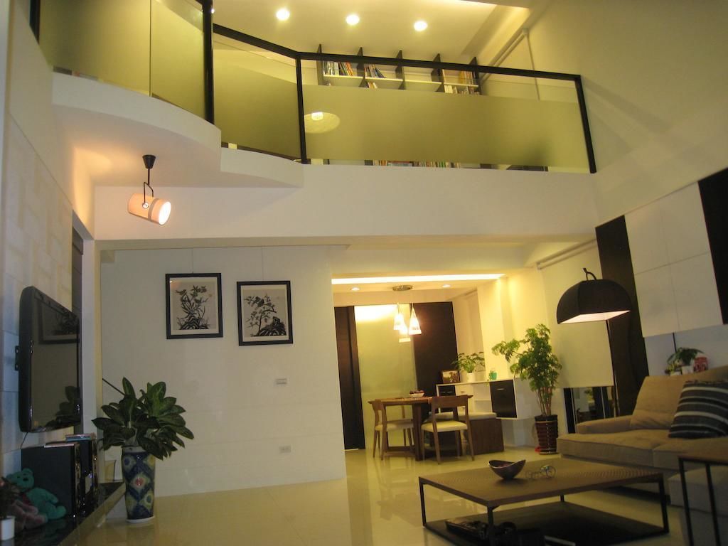 Uma sala de estar moderna com teto alto, área de refeições e escada que leva a um andar superior.