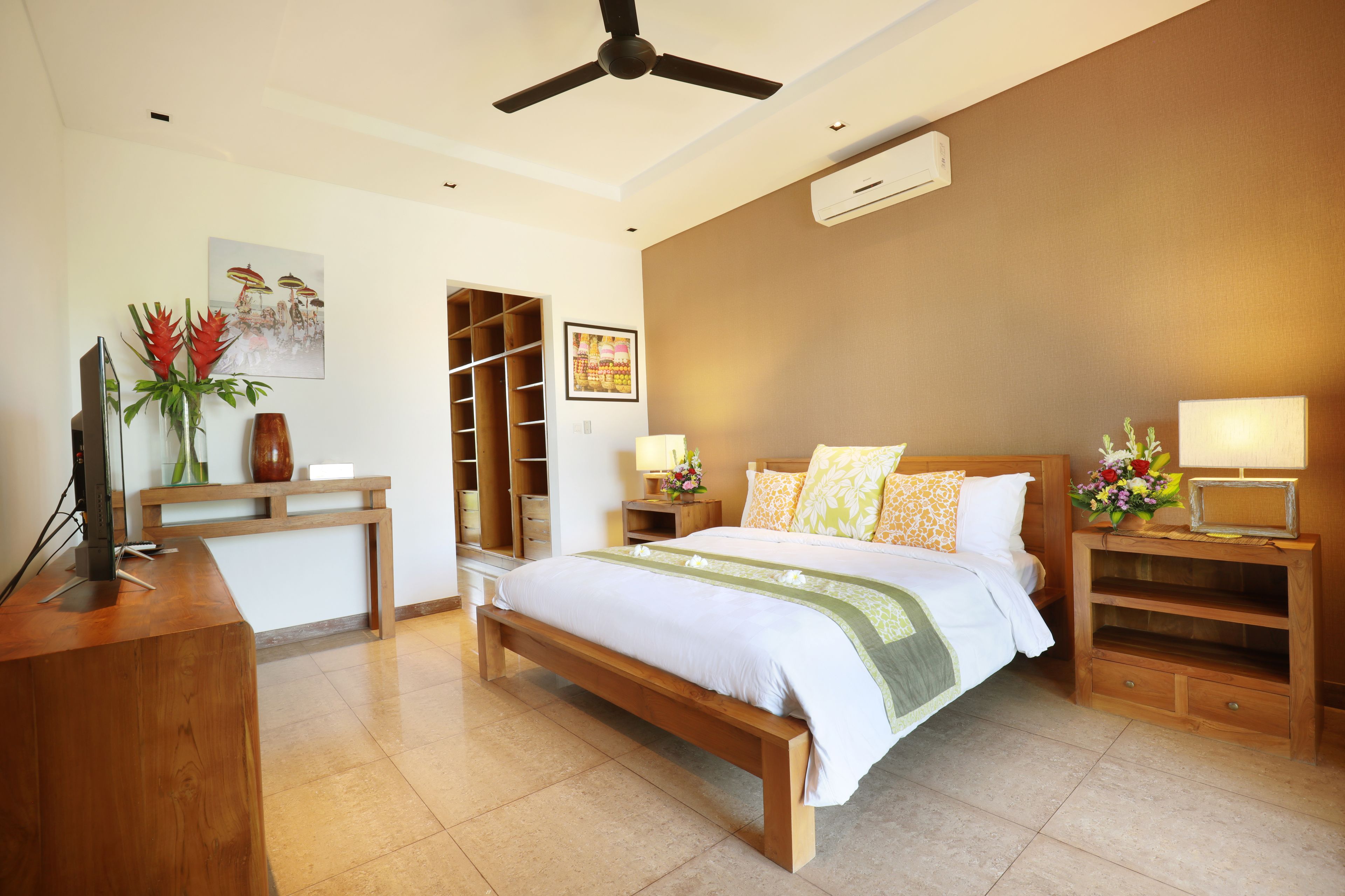 Quarto de hotel com cama, mesas de cabeceira, escrivaninha e televisão.