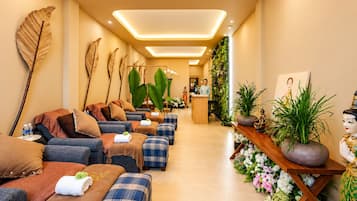 Espaço de spa com diversas opções de assento, balcão de recepção e plantas decorativas.