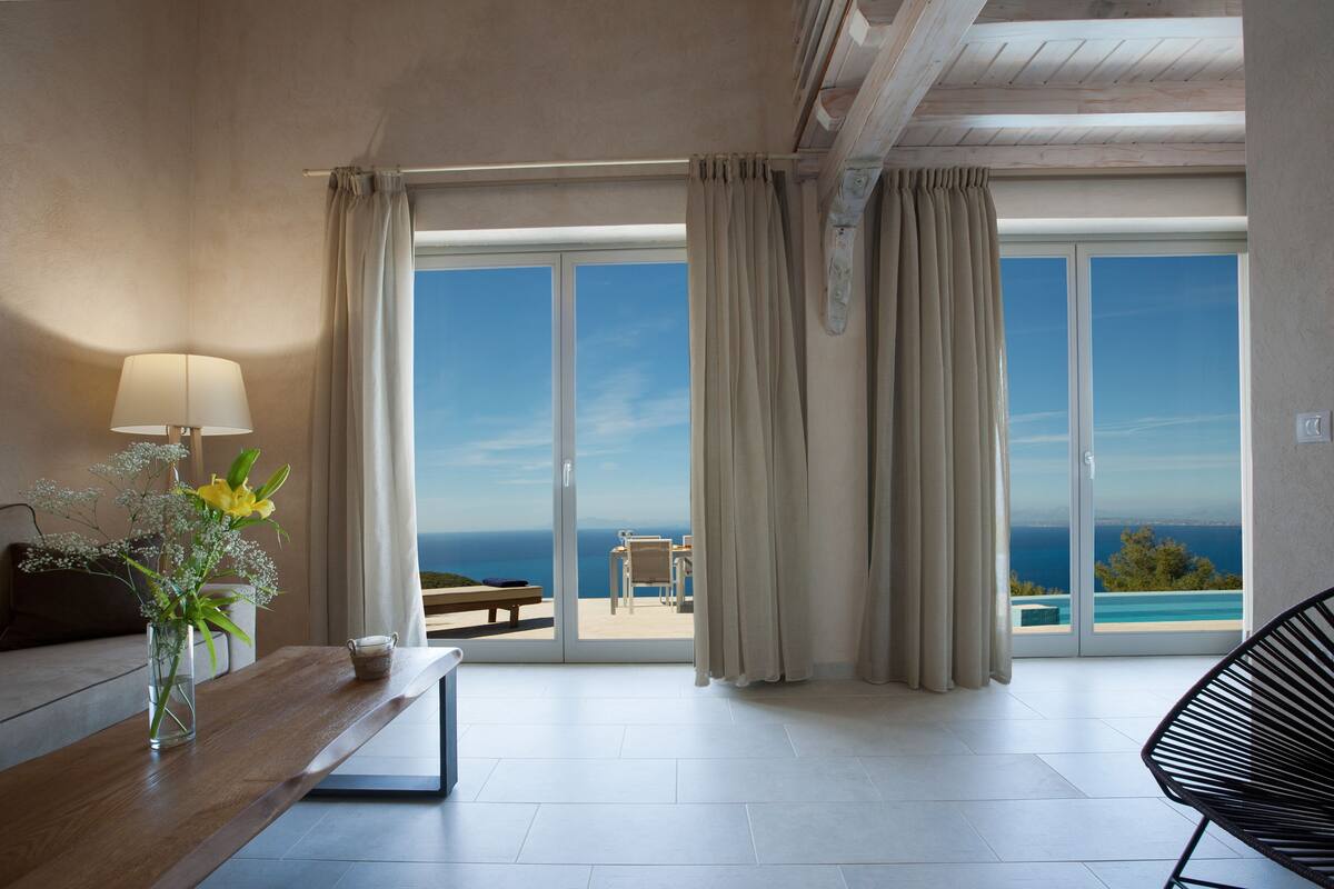 Quarto moderno com uma grande porta de vidro deslizante que dá para uma varanda com vista para o mar.