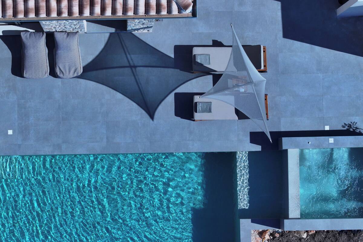 Vista aérea de um resort com piscina, área de estar e assentos com sombra.