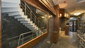 Um interior moderno com escada, paredes de mármore e detalhes em madeira.