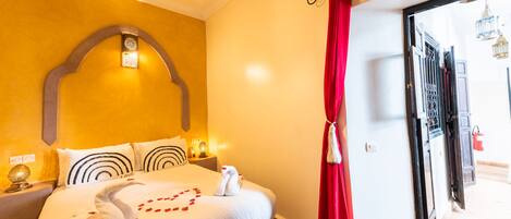 Quarto de hotel com cama, lustre e cortina vermelha.