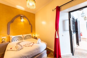 Quarto de hotel com cama, lustre e cortina vermelha.