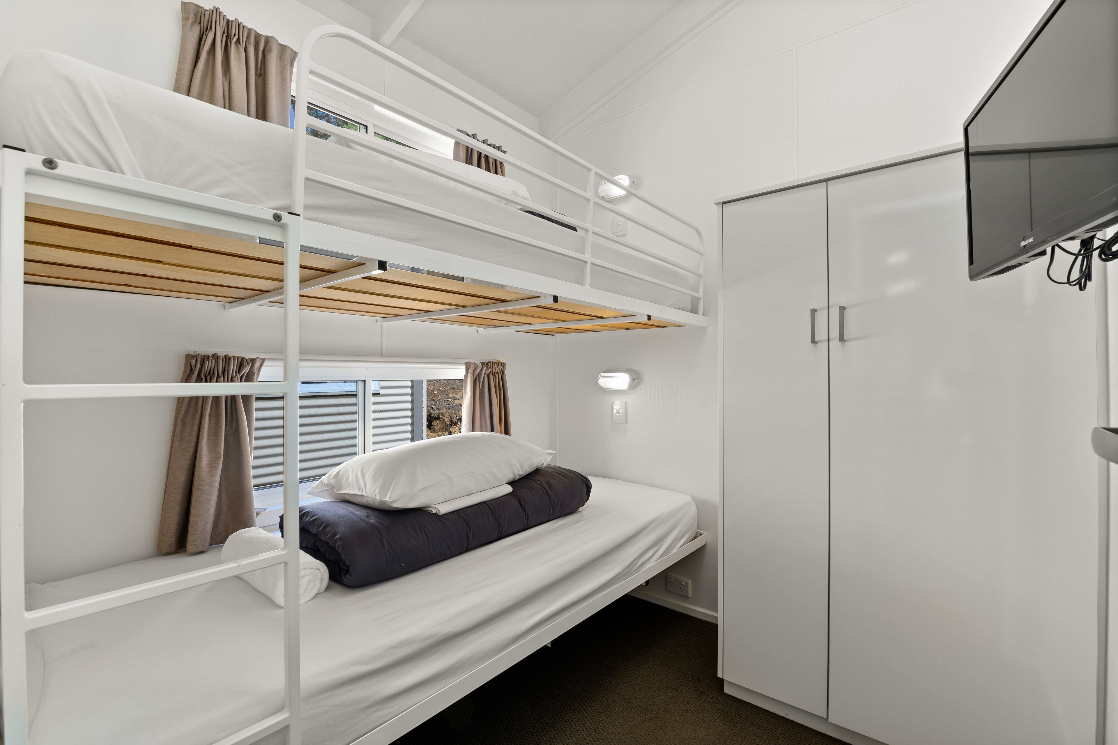Quarto com beliche, guarda-roupa e televisão.
