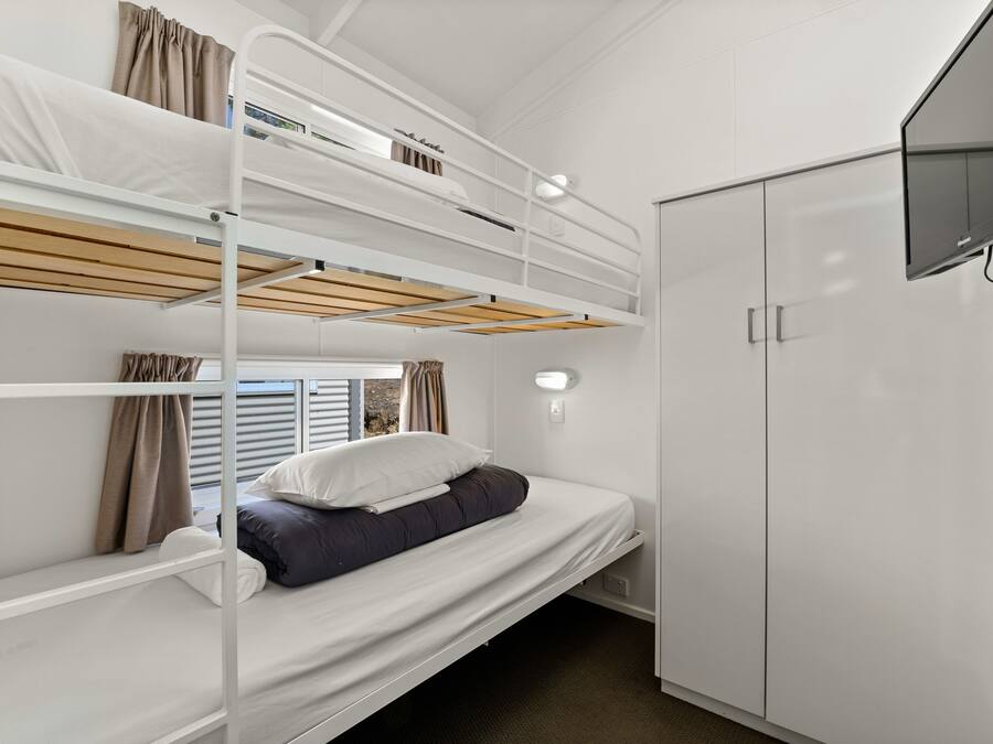 Quarto com beliche, guarda-roupa e televisão.