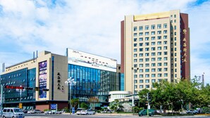 Um hotel moderno com fachada de vidro marcante, vários andares e um grande letreiro com caracteres chineses.