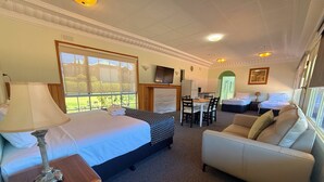 Quarto de hotel com cama, sofá, mesa de jantar e televisão.