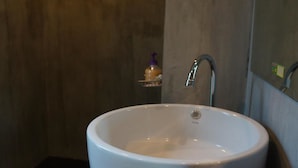 Casa de banho com lavatório branco, espelho e porta-toalhas.