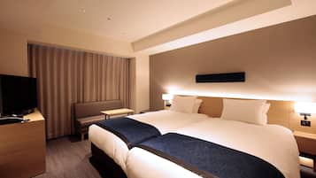 Quarto de hotel com uma cama grande, televisão, escrivaninha e uma cadeira.