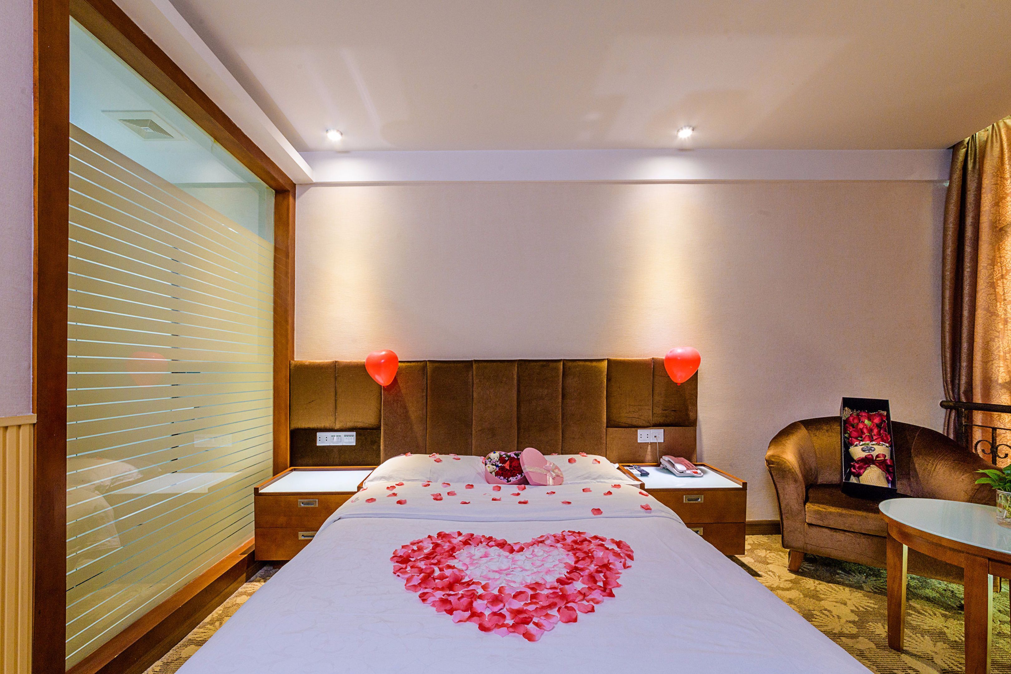 Quarto de hotel com cama, mesa de cabeceira, uma cadeira e uma pequena mesa.