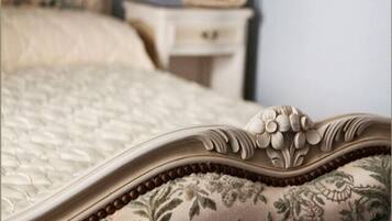 Cama com cobertura estampada floral e cabeceira decorativa.
