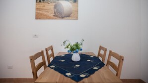 Uma mesa de jantar com toalha azul, cadeiras de madeira e um vaso com flores.