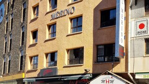 Hotel com vários andares, restaurante no andar térreo e uma faixa de pedestres à frente.