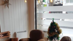 Uma sala de estar acolhedora com piso de madeira, sofás de couro marrom, uma poltrona estampada e uma pequena árvore de Natal.
