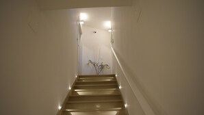 Uma escadaria com degraus de madeira e luminárias na parede.