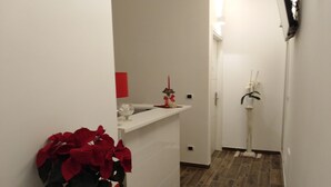 Um corredor estreito com parede branca, assoalho de madeira e uma porta branca no final.