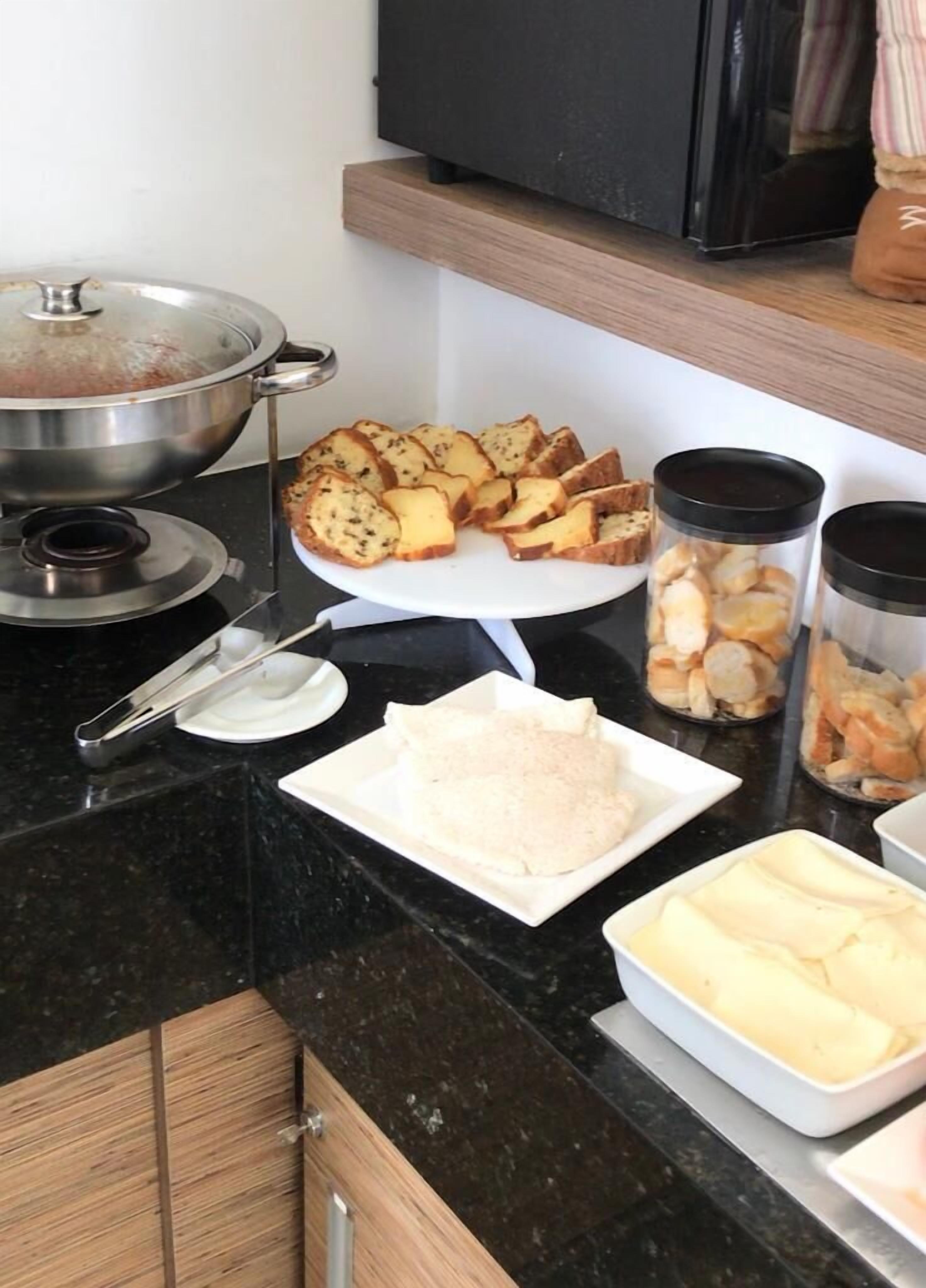 Uma bancada de cozinha com uma panela, pão fatiado, potes de biscoitos e um prato de pão sírio.