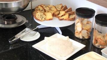 Uma bancada de cozinha com uma panela, pão fatiado, potes de biscoitos e um prato de pão sírio.