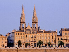 Um edifício histórico com duas torres imponentes, uma entrada central e fachada simétrica.