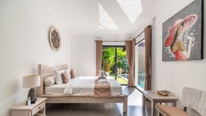 Quarto moderno com cama, mesa de cabeceira e um banco.