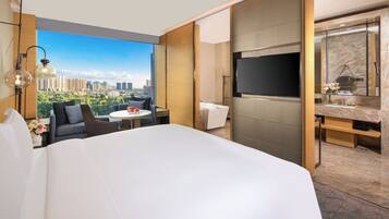 Quarto de hotel com cama grande, televisão, banheiro com espelho e vista para a cidade.