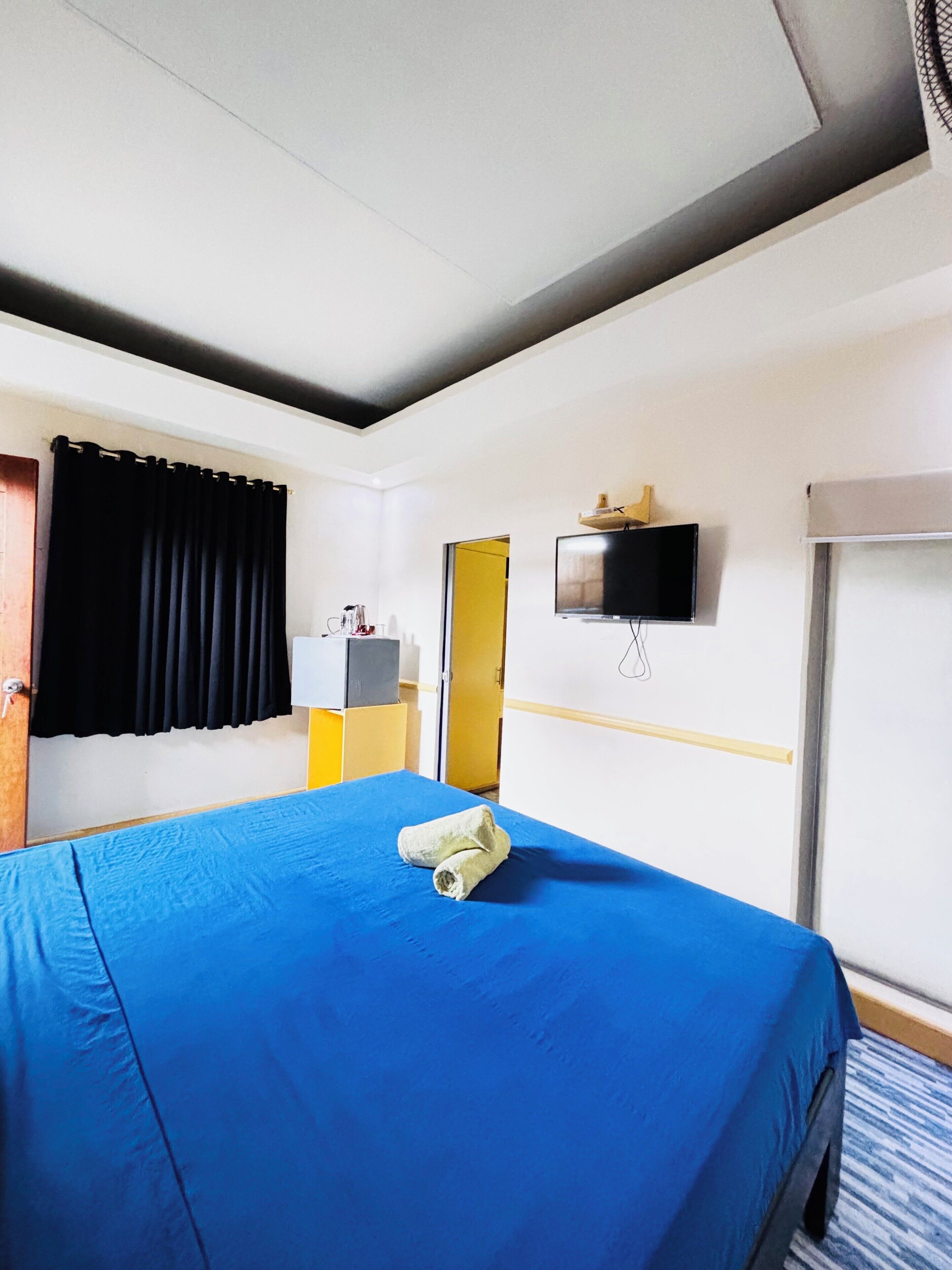 Quarto de hotel com cama, televisão, espelho e porta.