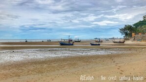 Uma praia com vários barcos ancorados na água, uma faixa de areia e um céu parcialmente nublado.