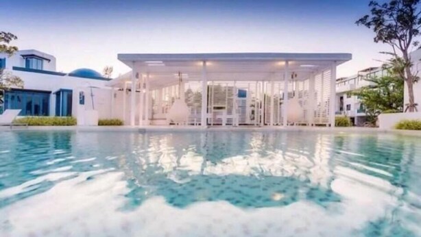 Uma área de piscina moderna, com um espaço coberto para sentar e vista direta para a piscina.