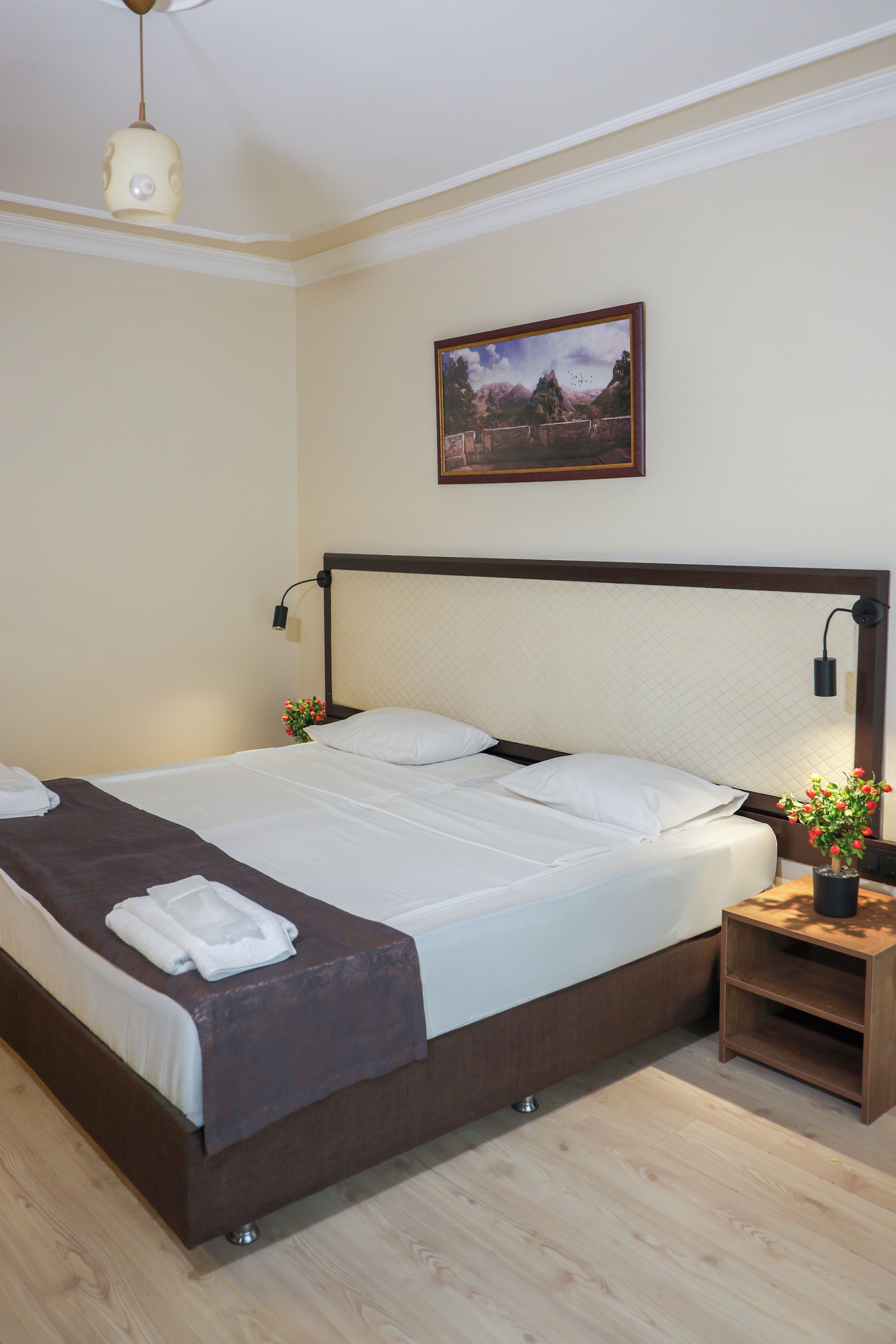 Cama bem arrumada com lençóis brancos e cabeceira marrom em quarto de hotel.