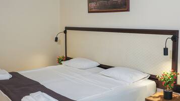 Cama bem arrumada com lençóis brancos e cabeceira marrom em quarto de hotel.