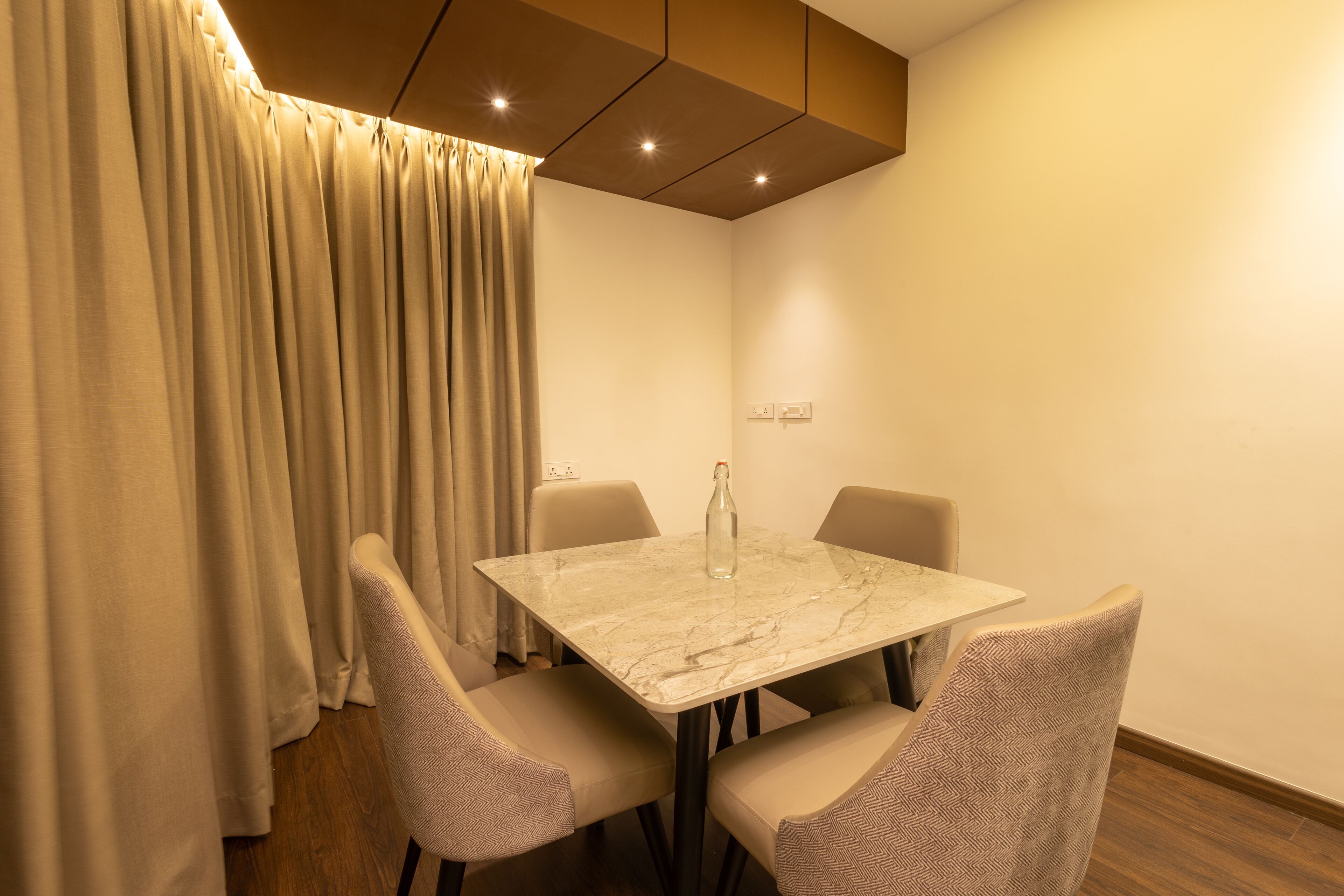 Uma área de refeições com uma mesa de mármore, quatro cadeiras e uma garrafa sobre a mesa.