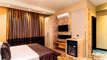 Quarto de hotel com cama, minibar, televisão e ar condicionado.