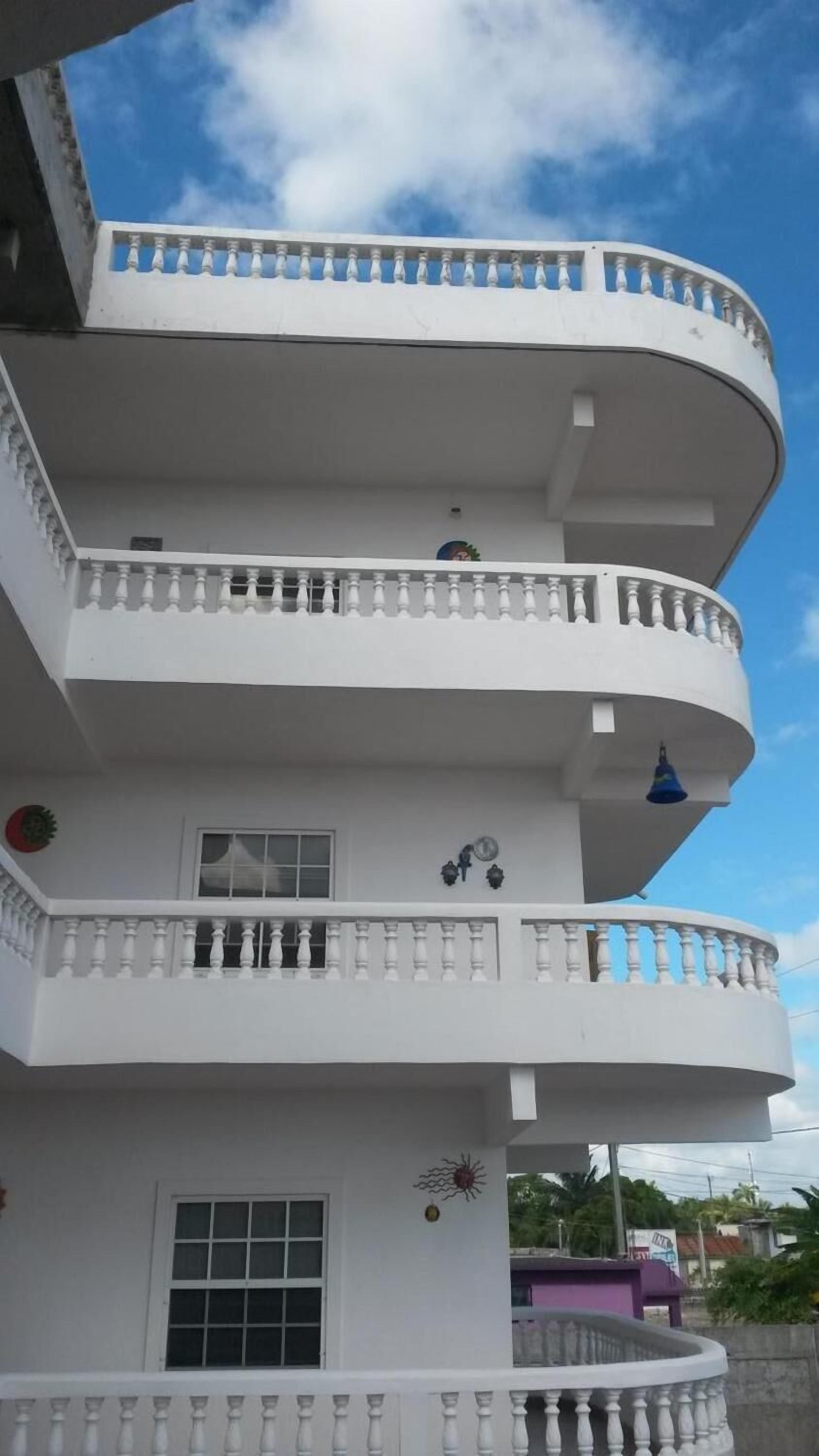 Um edifício com várias andares, varandas, uma janela e um sino.