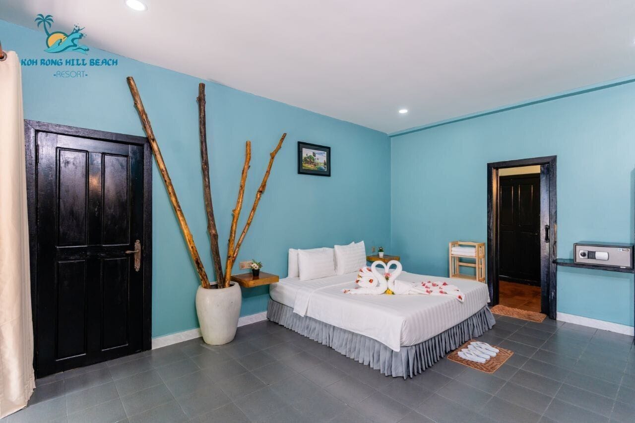 Quarto com cama, mesa de cabeceira, planta em vaso e um quadro na parede.