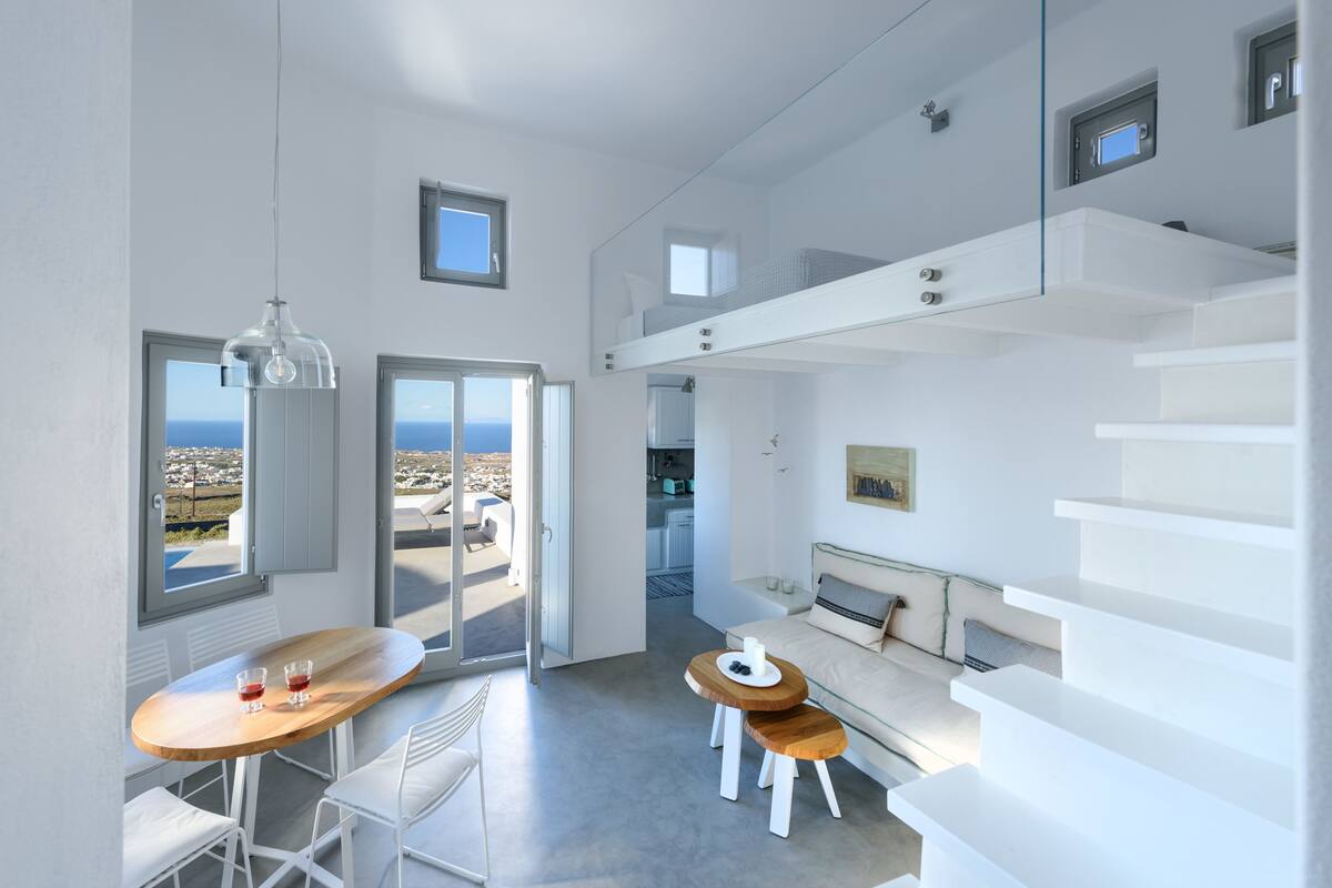 Quarto moderno e minimalista com área de refeições, um sofá e uma escada.